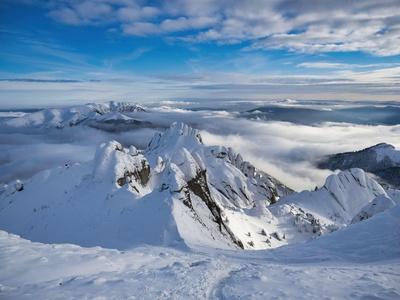Aerial view of distant mountain peaks above clouds in clear sunny blue ...