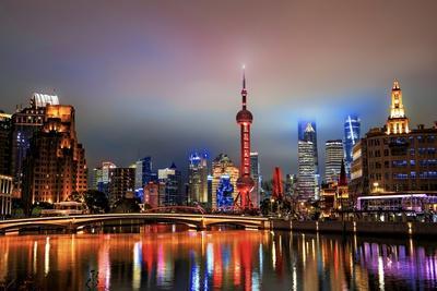 Brightly lit skyline of Lujiazui at night covered in mist viewed from ...