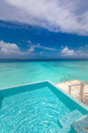 Infinity swimming pool with sea and ocean view on blue sky background ...