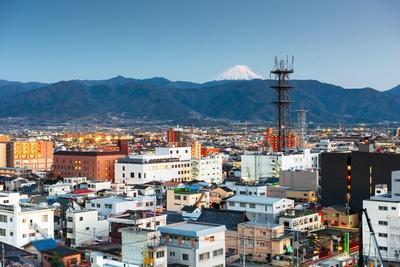 Kofu, Japan city skyline with Mt. Fuji peaking over the mountains at ...