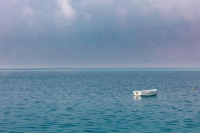 'Old rowing boat marooned at sea. Lonely wooden boat, cloudy sky, calm ...