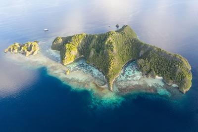 Rugged limestone islands rise from the serene seascape in Raja Ampat ...