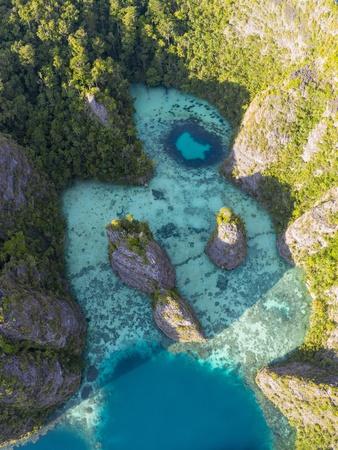 Seen from above, remote islands are surrounded by coral reefs in Raja ...