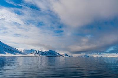 'Snow covered mountains rise near the shore of Mushamna Bay. Spitsbergen Island, Svalbard ...