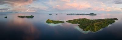 Sunrise illuminates clouds that drift over the calm waters of the ...