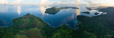 Sunrise illuminates clouds that drift over the calm waters of the ...