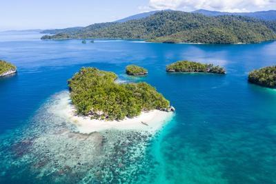 The many tropical islands within Raja Ampat, Indonesia, are surrounded ...