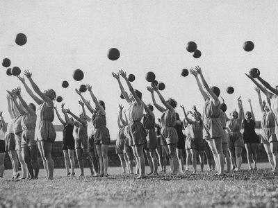 'Women's Gym Class with Rows of Women Throwing Balls Into Air in Unison ...